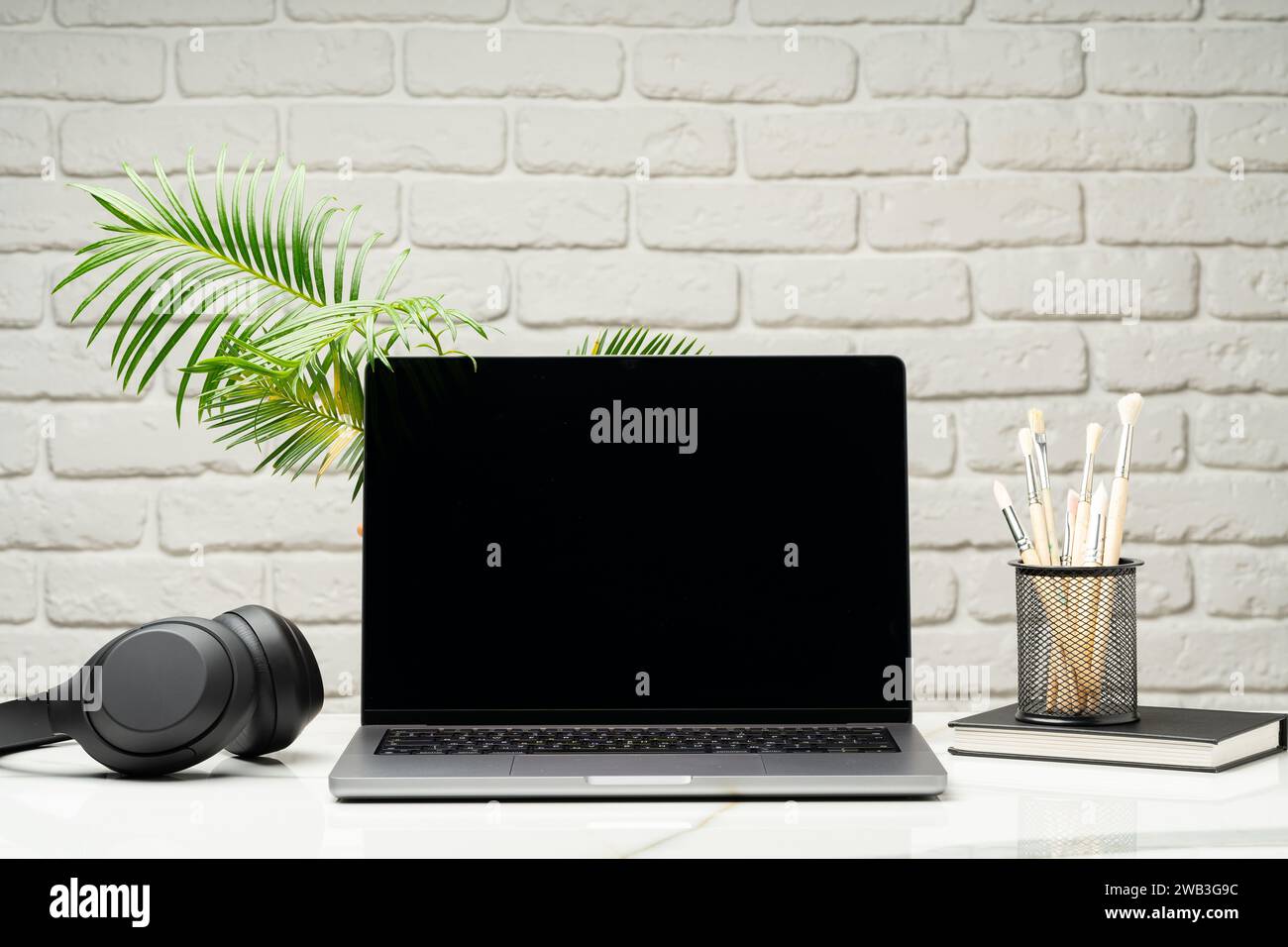 Laptop with black screen on desk against white brick wall Stock Photo ...