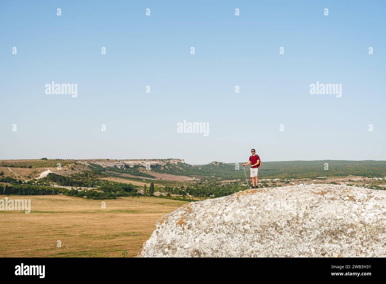 Full body of male traveler standing on rocky mountain on summer day ...