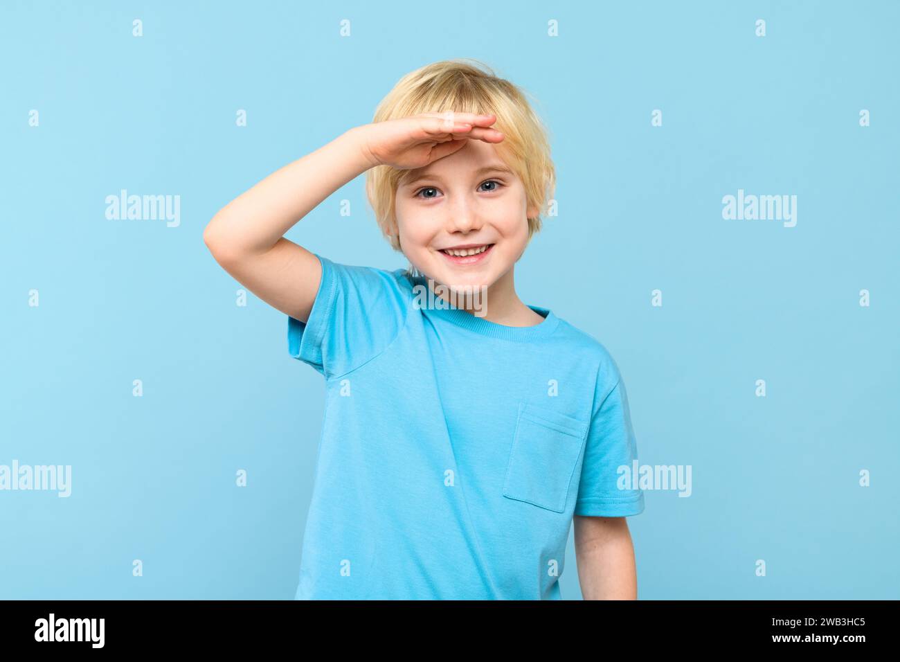 Cute preschooler looking to distance with hand on the forehead, smiling ...