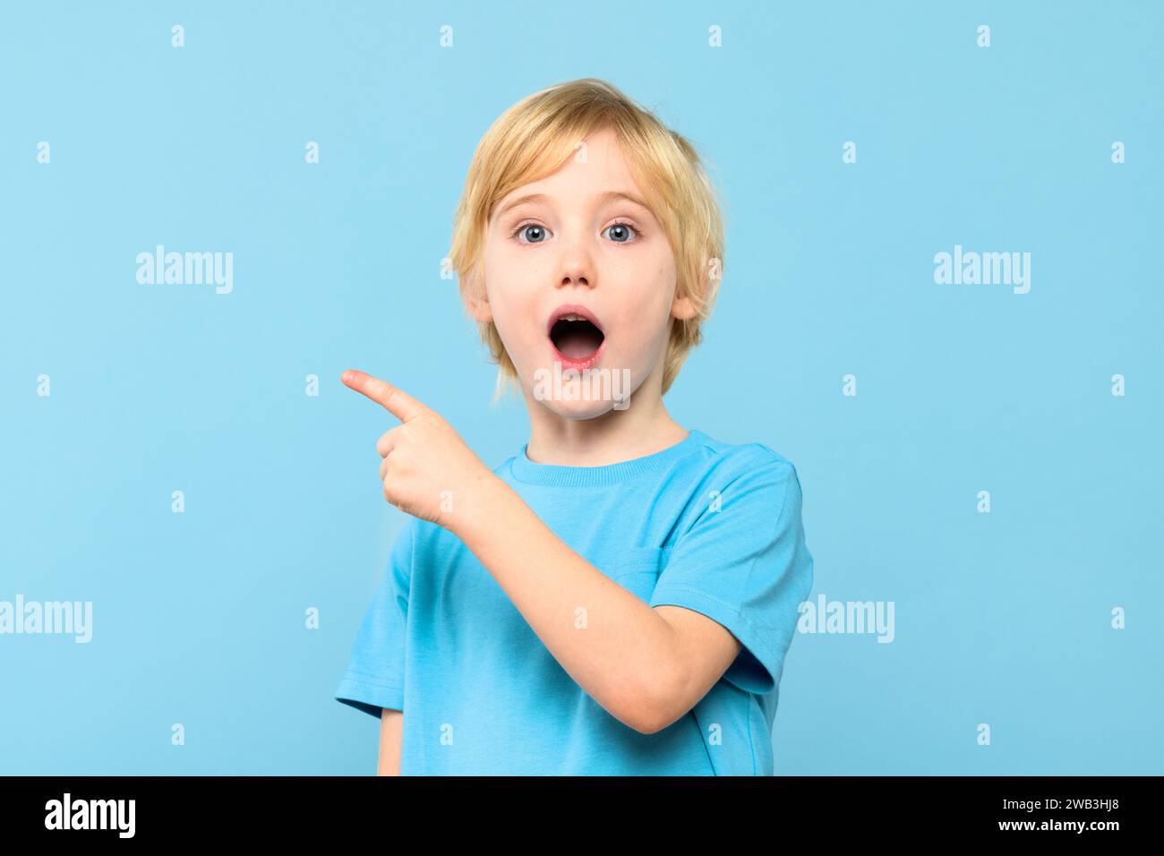 Wow! Portrait of a shocked cute little boy with blond hair pointing to ...