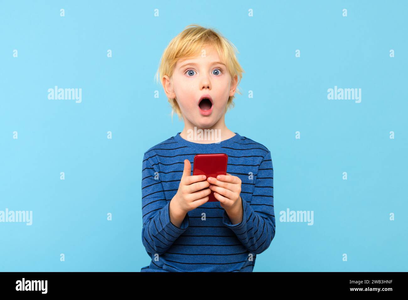 Young child holding smartphone, shocked with mouth open in disbelief ...