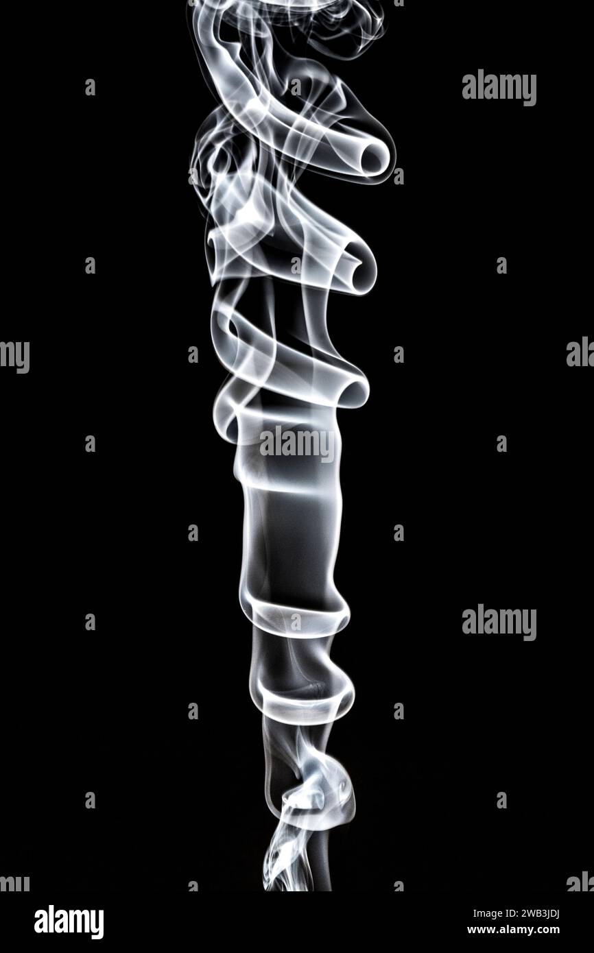 A studio photograph of incense smoke rising against a black background ...