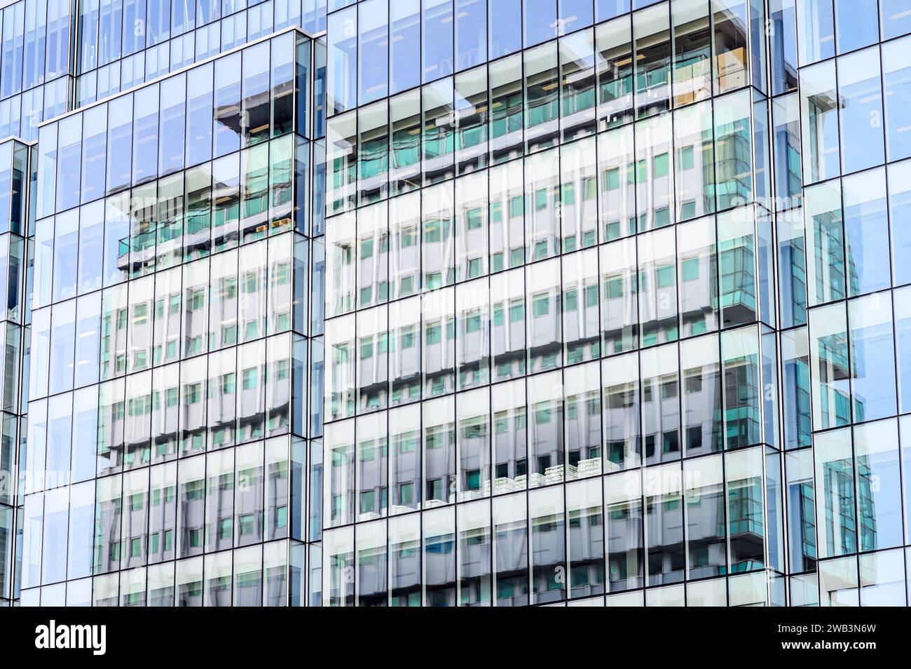 High rise residential tower block reflected in the glass facade of an ...