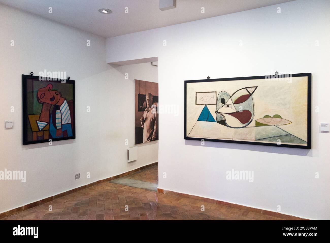 Room with two paintings either side of a portrait photograph of Picasso ...