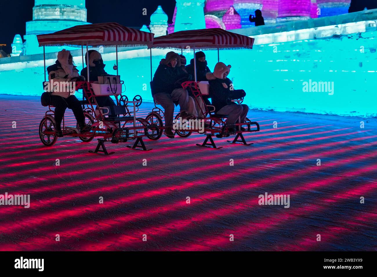 Visitors ride a rented cart passing by ice sculpture at the annual ...