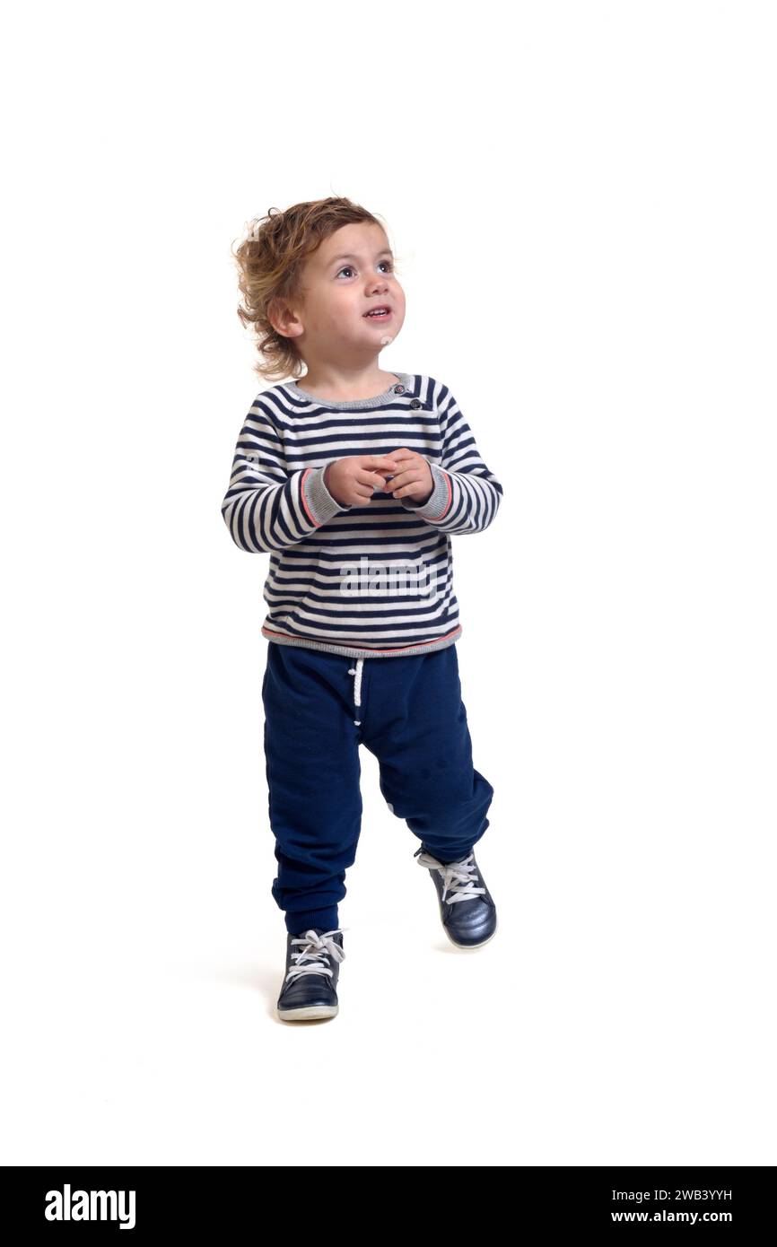 front view of a baby boy walking and looking up on white background ...