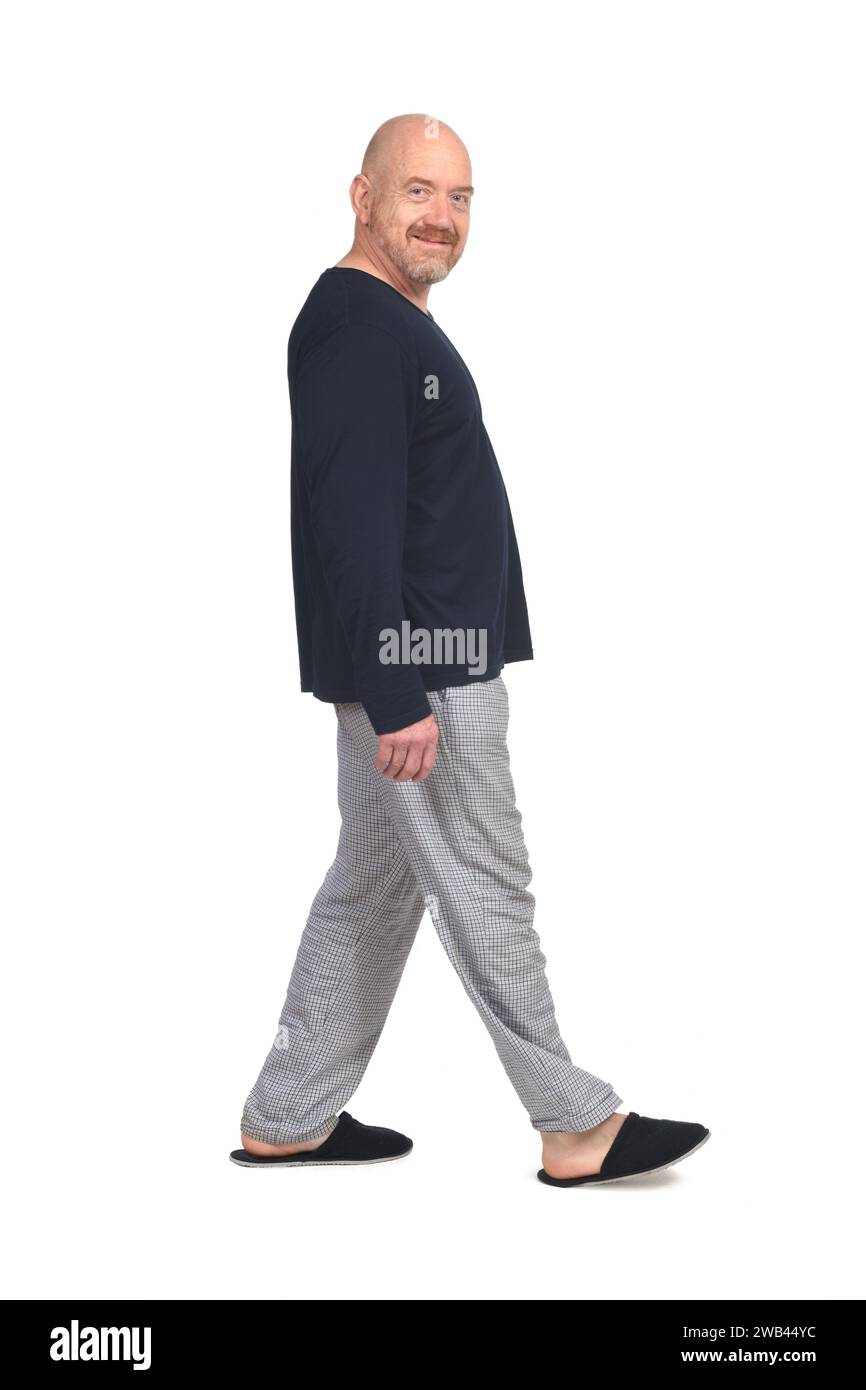 side view of a man in pajamas walking and looking at camera on white ...