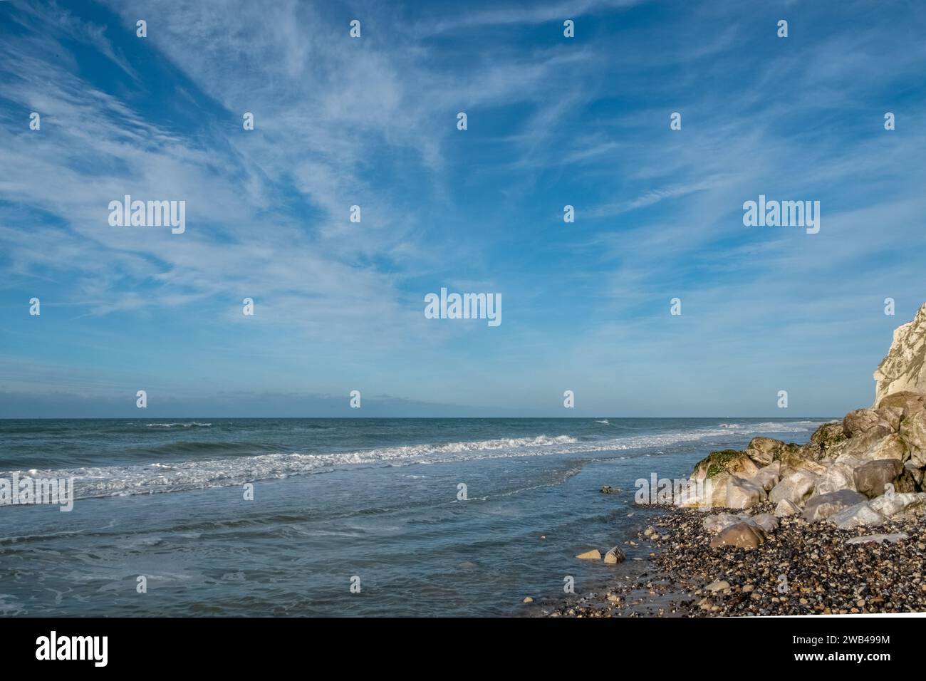 This striking image contrasts the smooth, undulating waves of the sea ...
