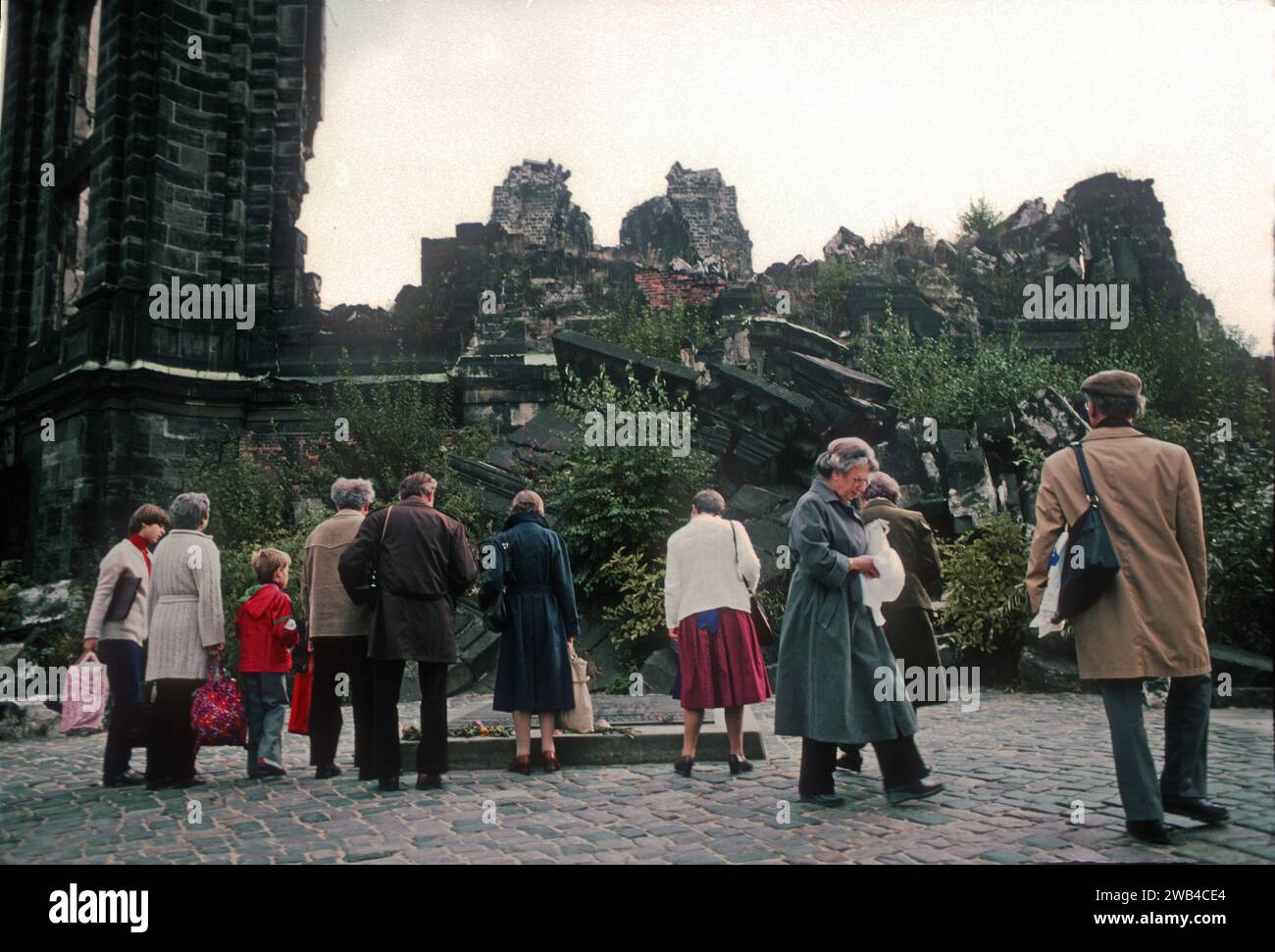 Germans passing in front of a building in ruins, damaged by bombing ...