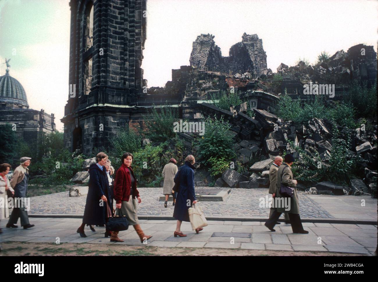 Germans passing in front of a building in ruins, damaged by bombing ...