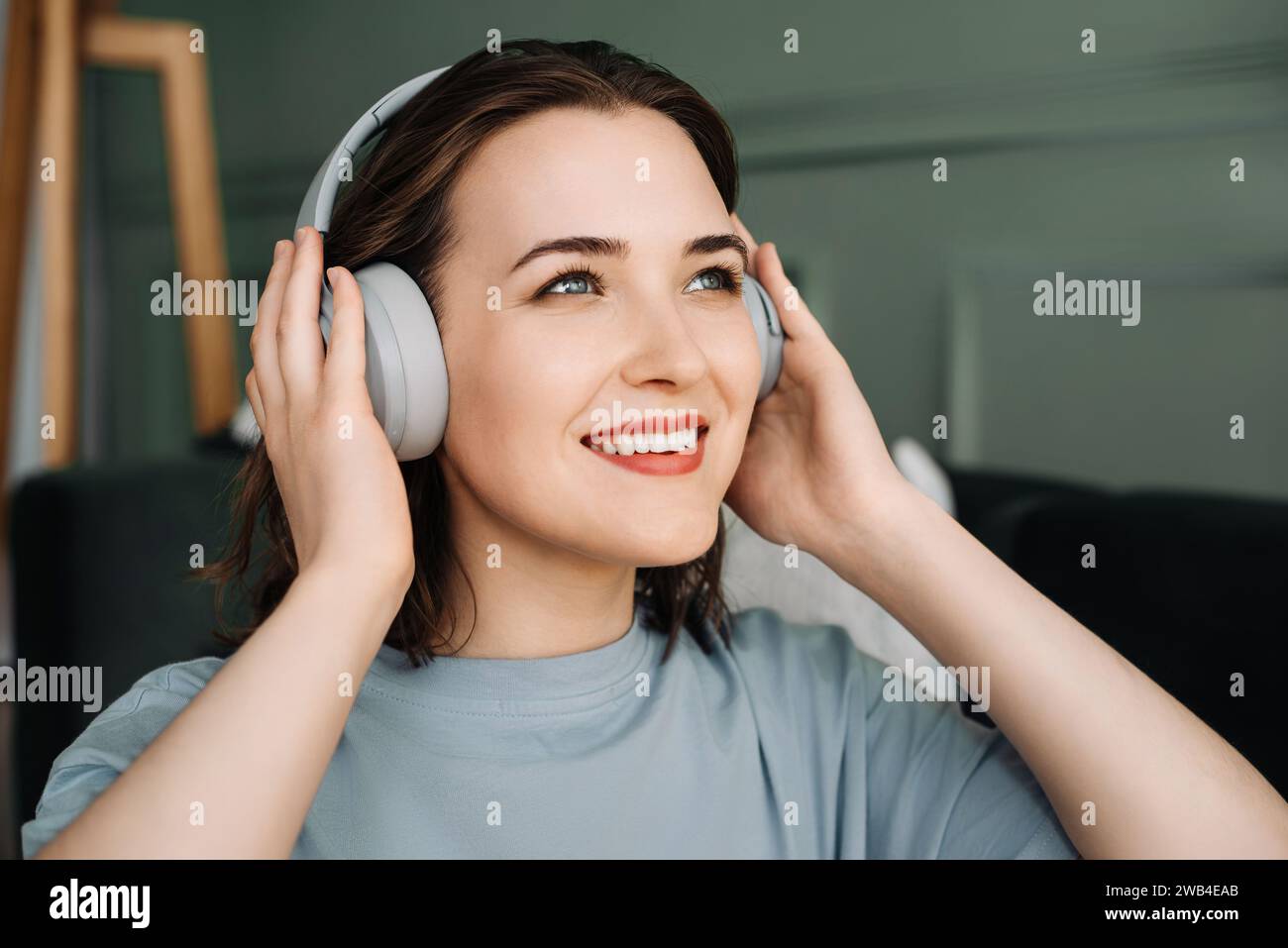 A smiling young middle-aged woman wearing wireless headphones listens to music. Musical Bliss ...