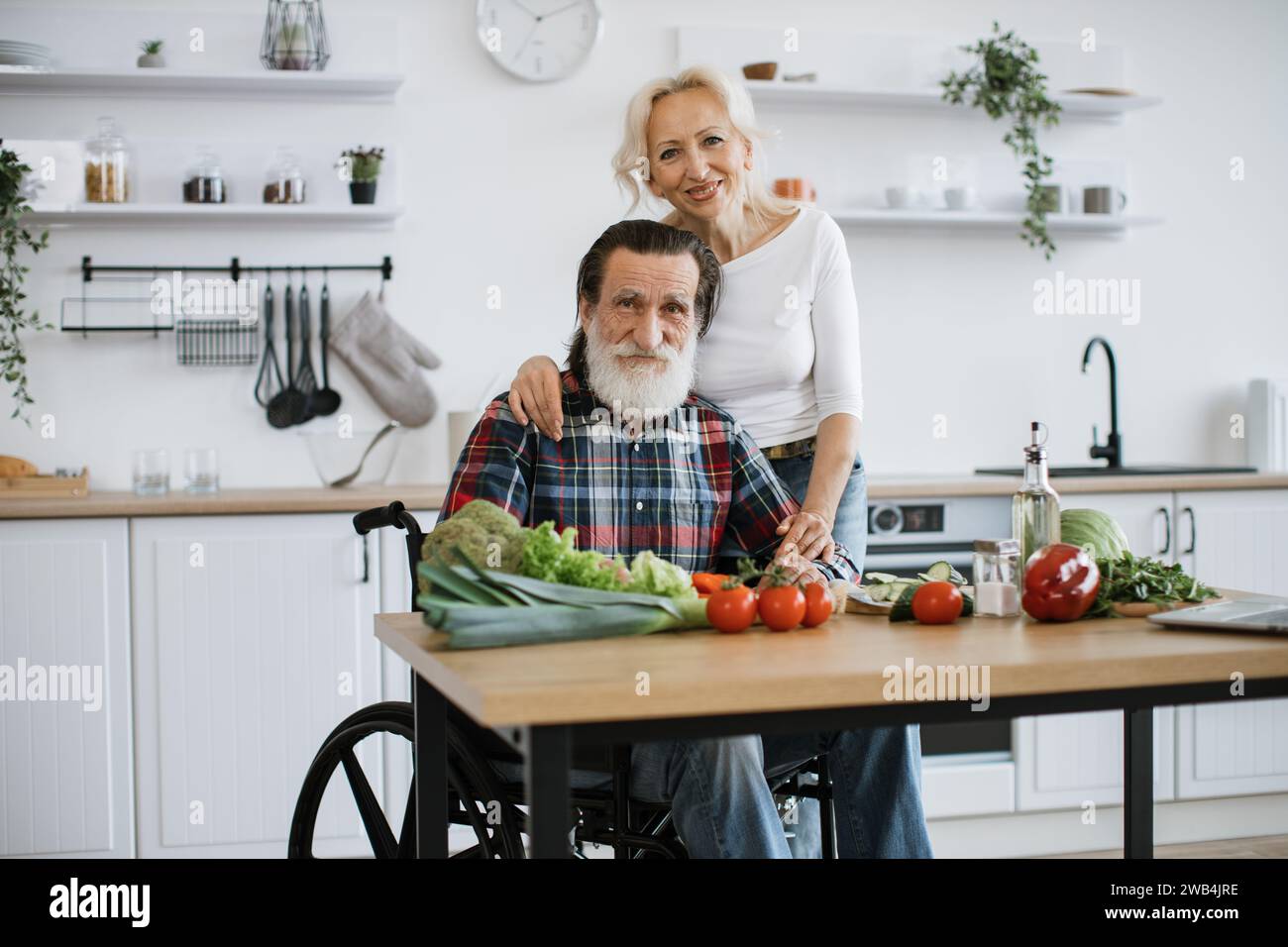 Disabled man with gray beard and wife preparing healthy vegetable salad ...