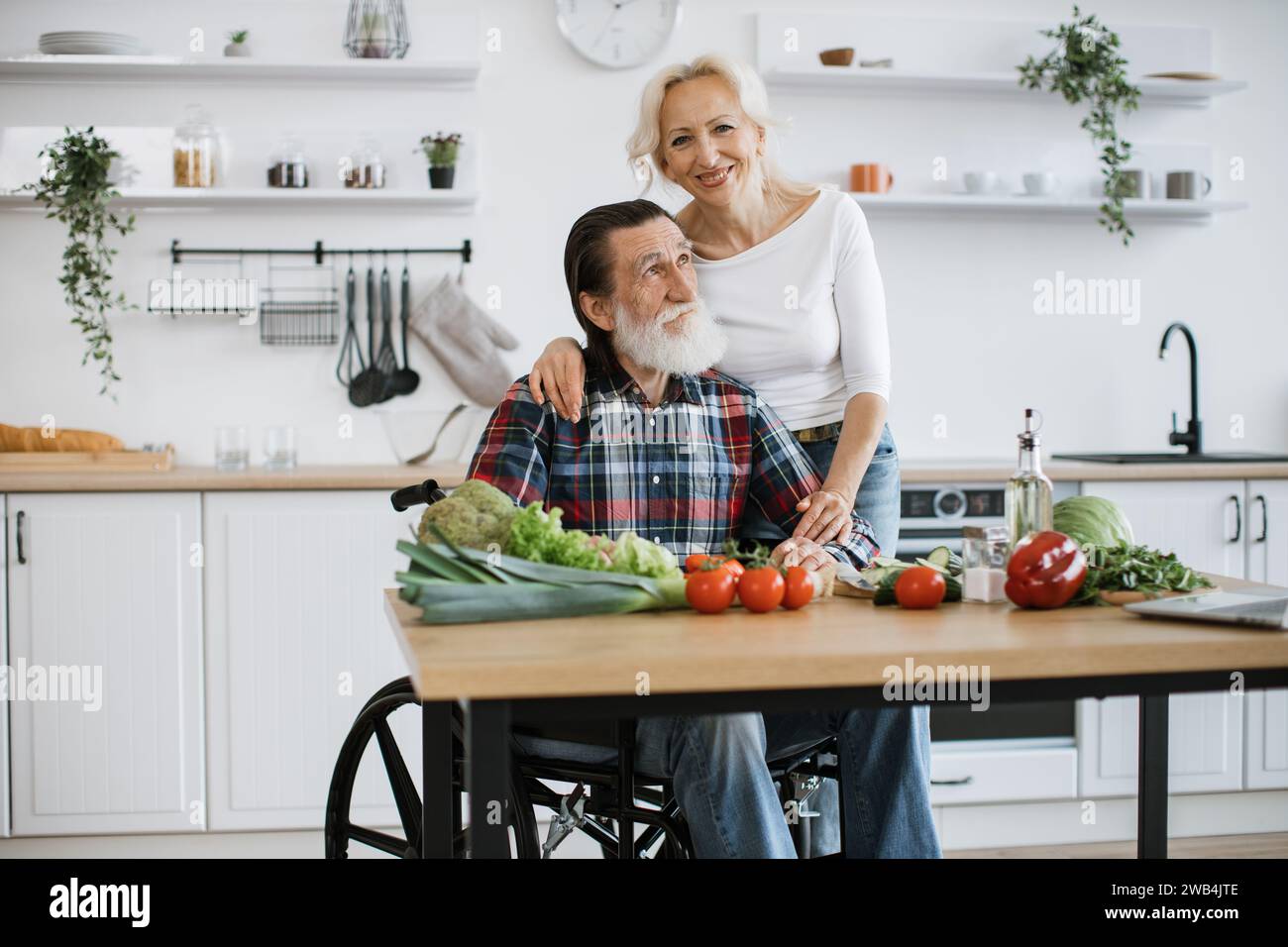 Disabled man with gray beard and wife preparing healthy vegetable salad ...