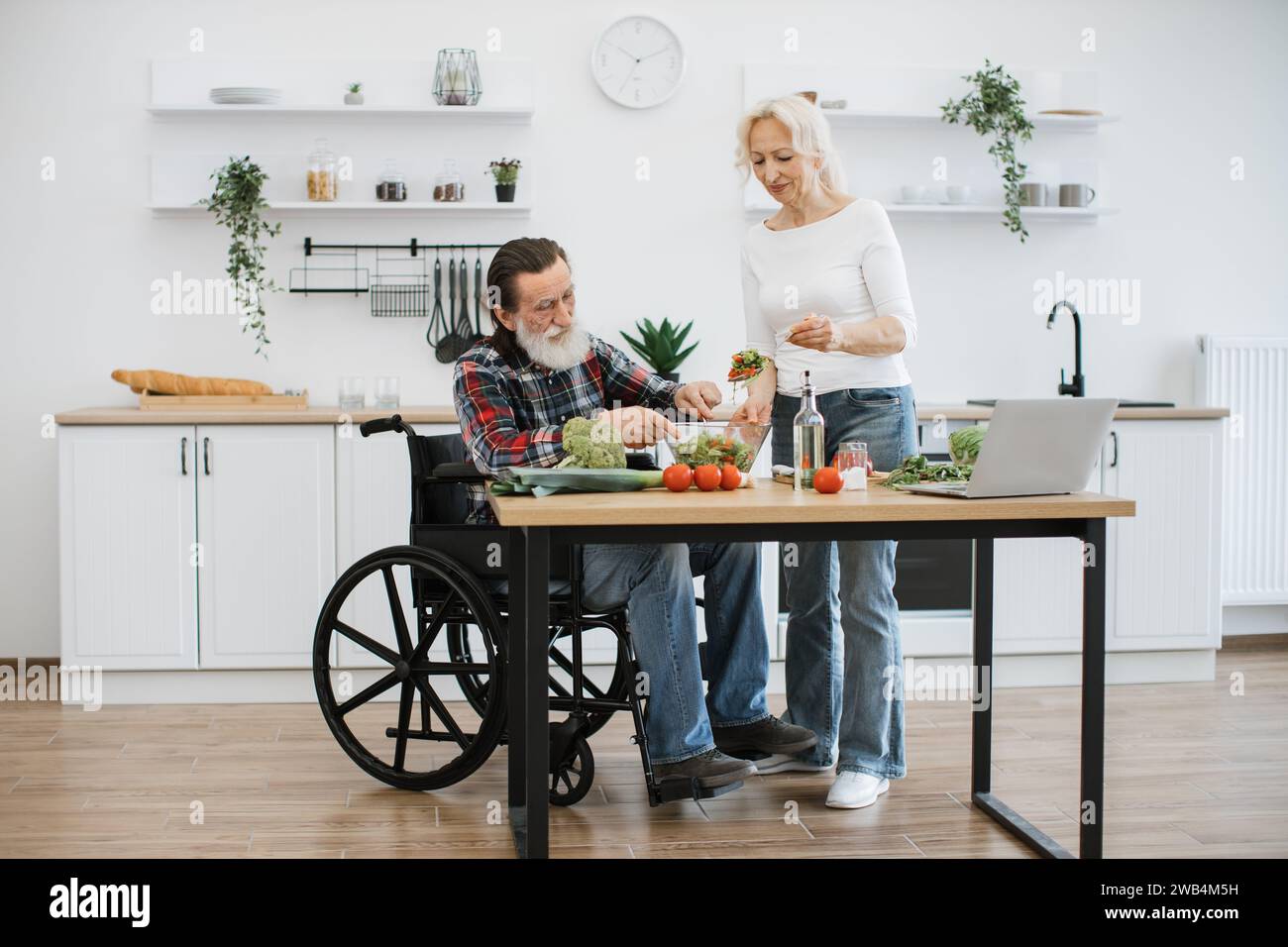 Old couple with disability spends time cooking breakfast in modern ...