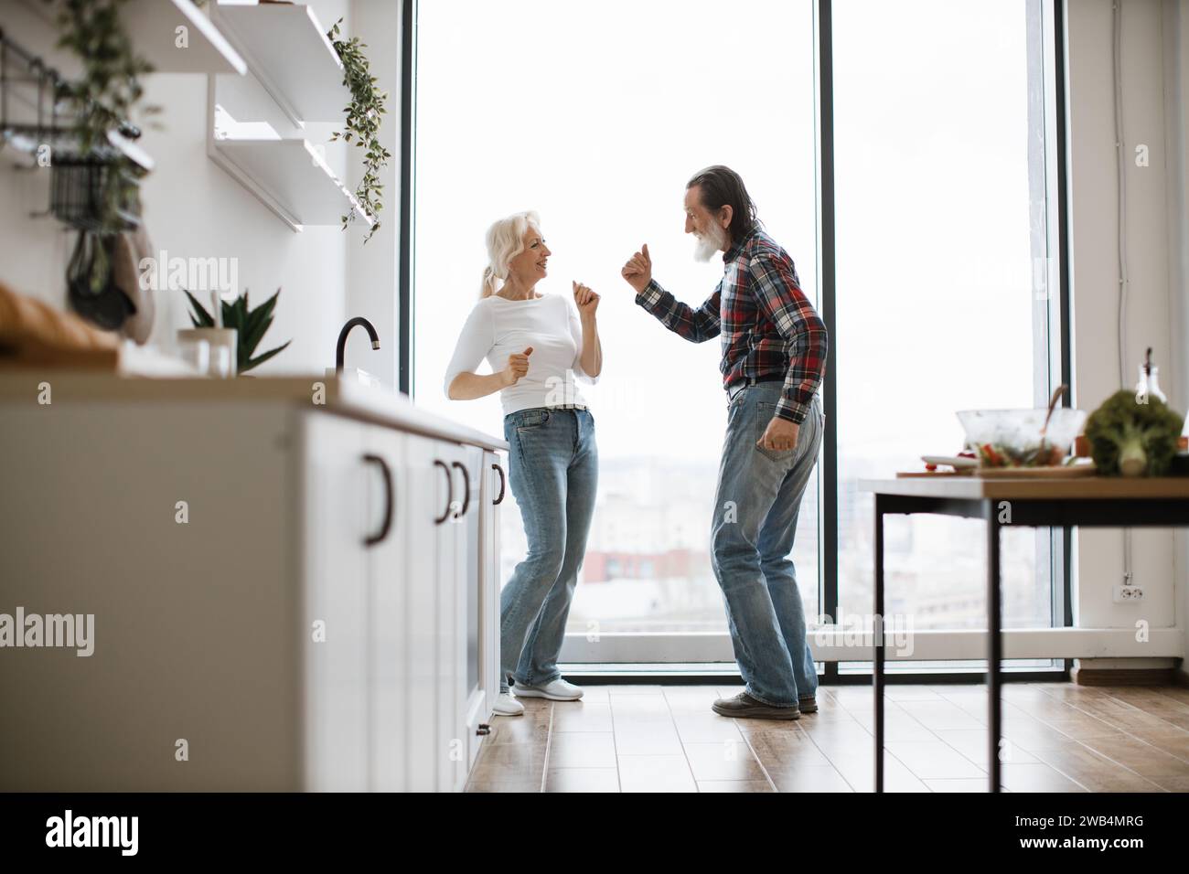 Old couple spends free time dancing twist in modern light kitchen Stock ...