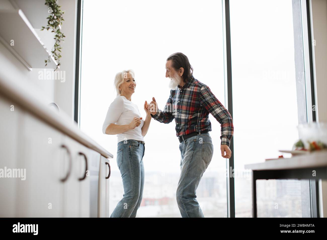 Old couple spends free time dancing twist in modern light kitchen Stock ...