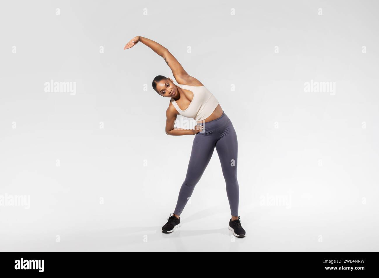 Black Lady Stretching Raised Arm While Bending Core, White Background ...