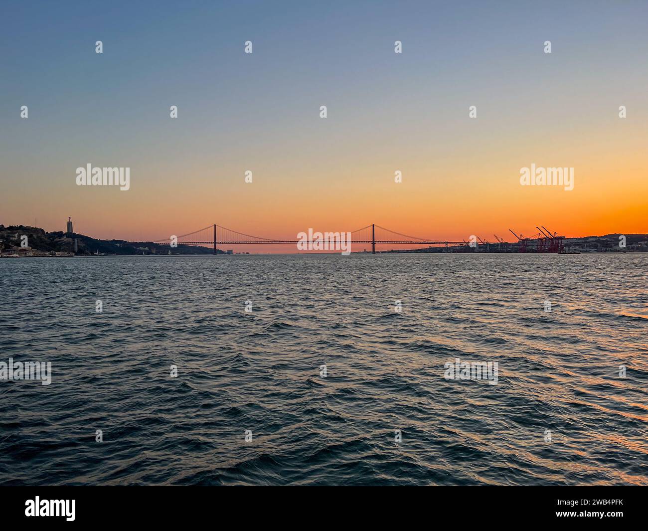Sunset over Lisbon seen from Tagus River with the 25th April Bridge in ...