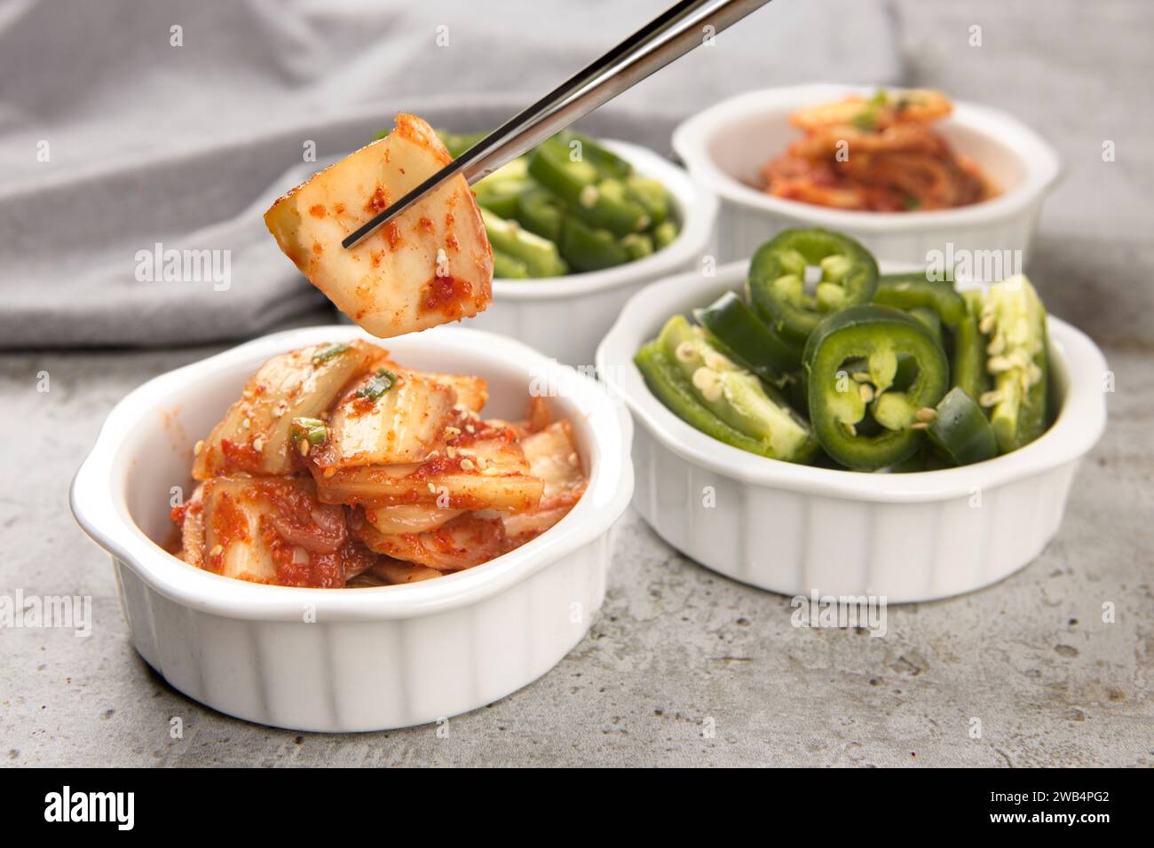A food photo of a pair of chopsticks holding a piece of kimchi above ...