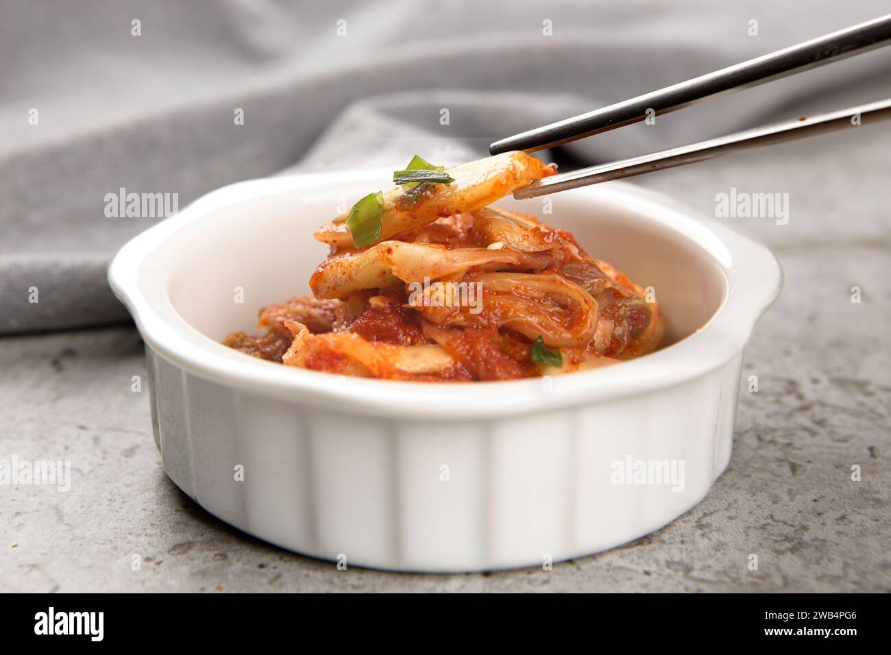 A close up photo of slices of Korean kimchi in a bowl and chopsticks ...