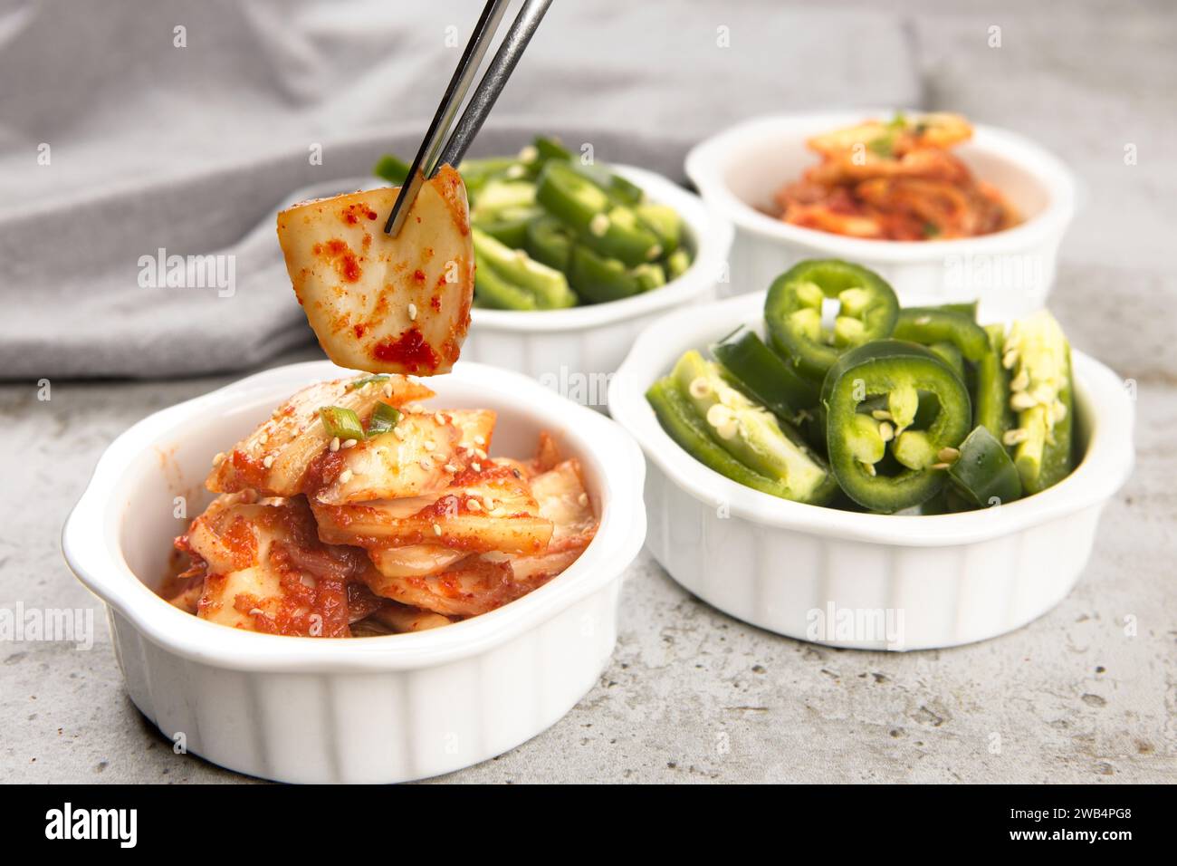 A food photo of a pair of chopsticks holding a piece of kimchi above ...