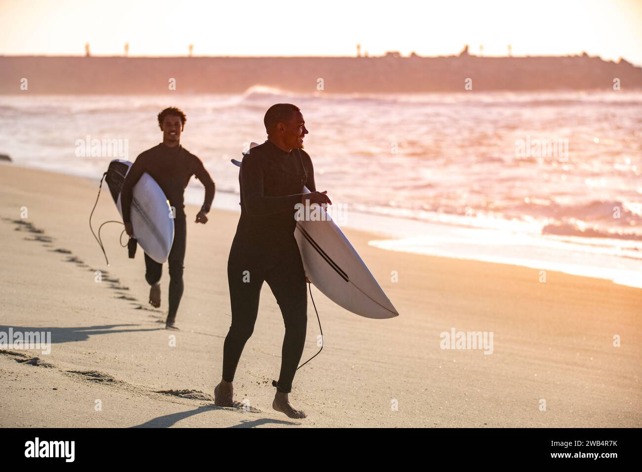 Two surfers run in the beach near the ocean with surfboard Stock Photo ...