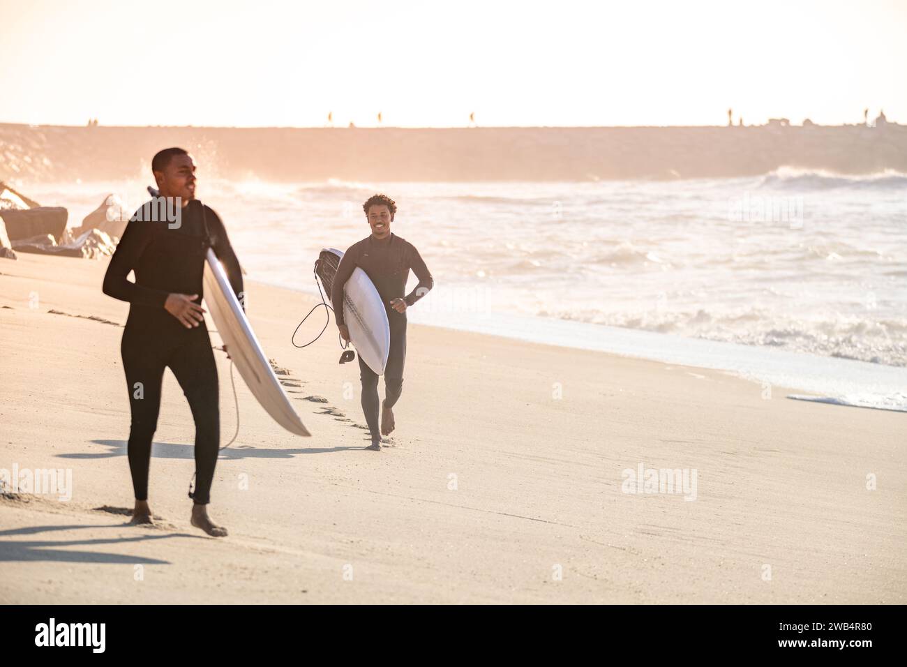 Two surfers run in the beach near the ocean with surfboard Stock Photo ...