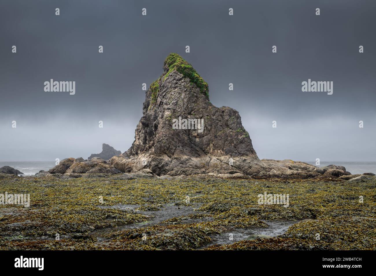 A large rock formation is situated on the edge of a tranquil lake Stock ...