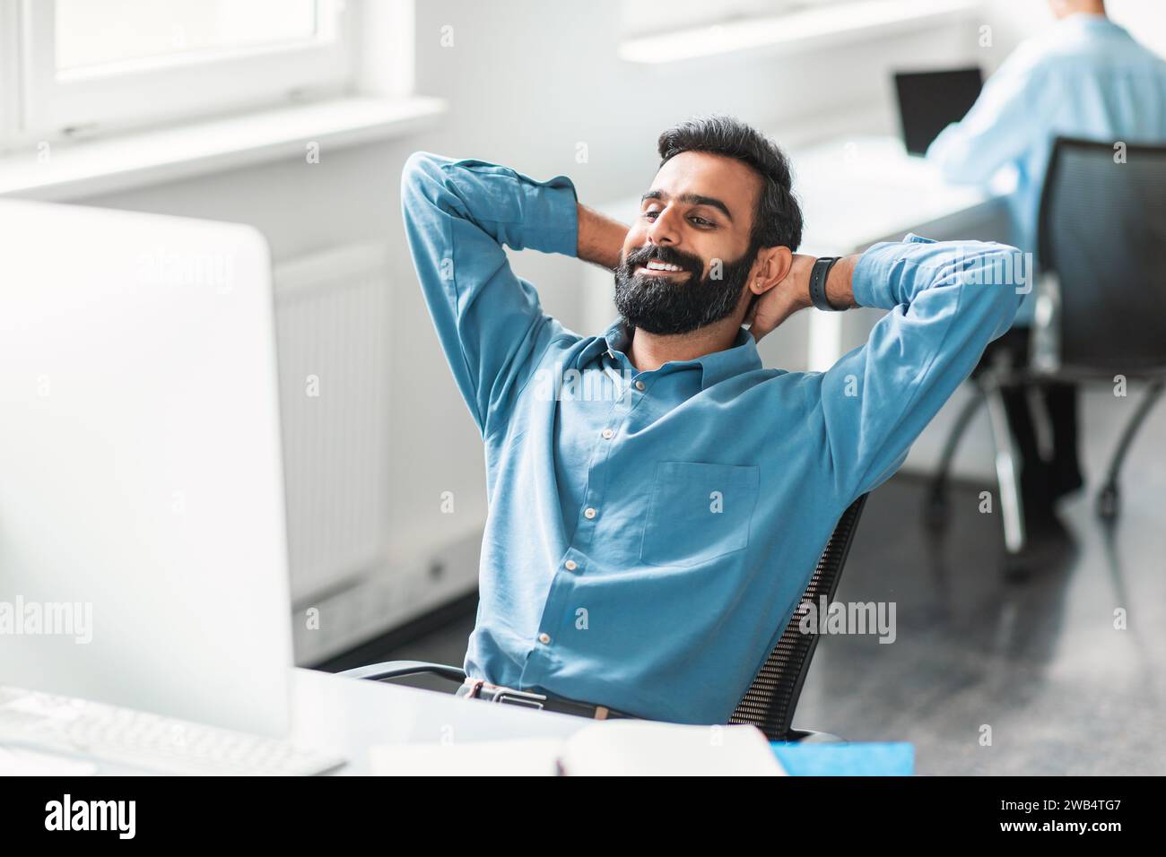 Relaxed indian male office worker leaning back in his chair, smiling Stock Photo - Alamy