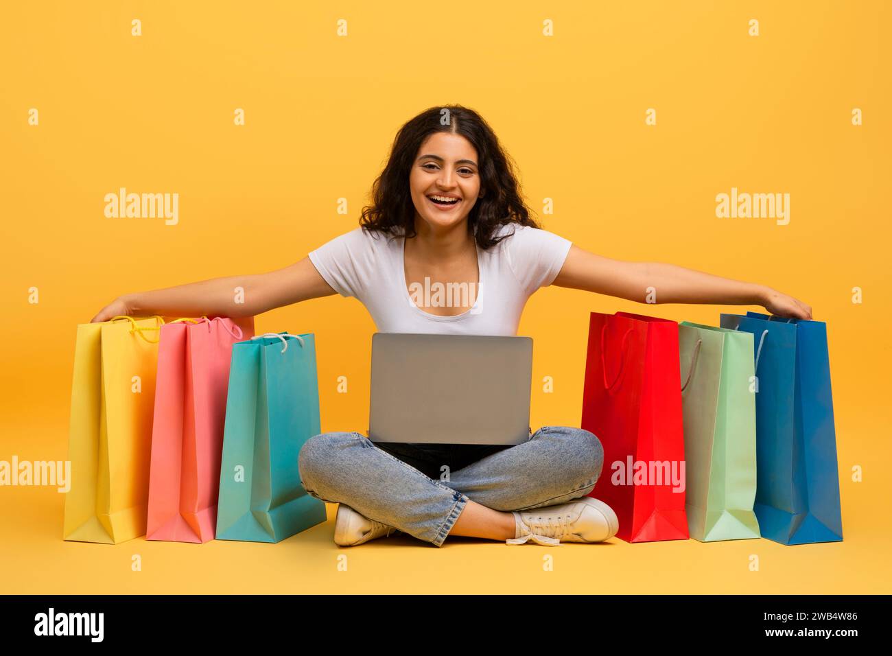 Young indian woman shopaholic using laptop, yellow background Stock ...