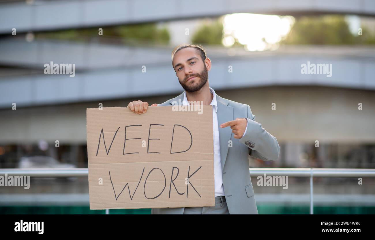 Young man holding 'Need Work' sign, illustrating the search for ...