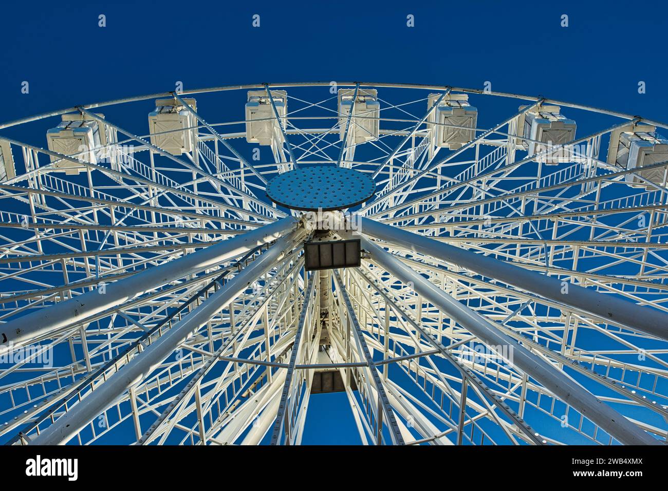 Ferris wheel against a clear blue sky, symmetrical view from below in ...