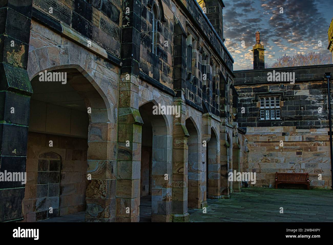 Historic stone building with archways under a dramatic sky at dusk in ...