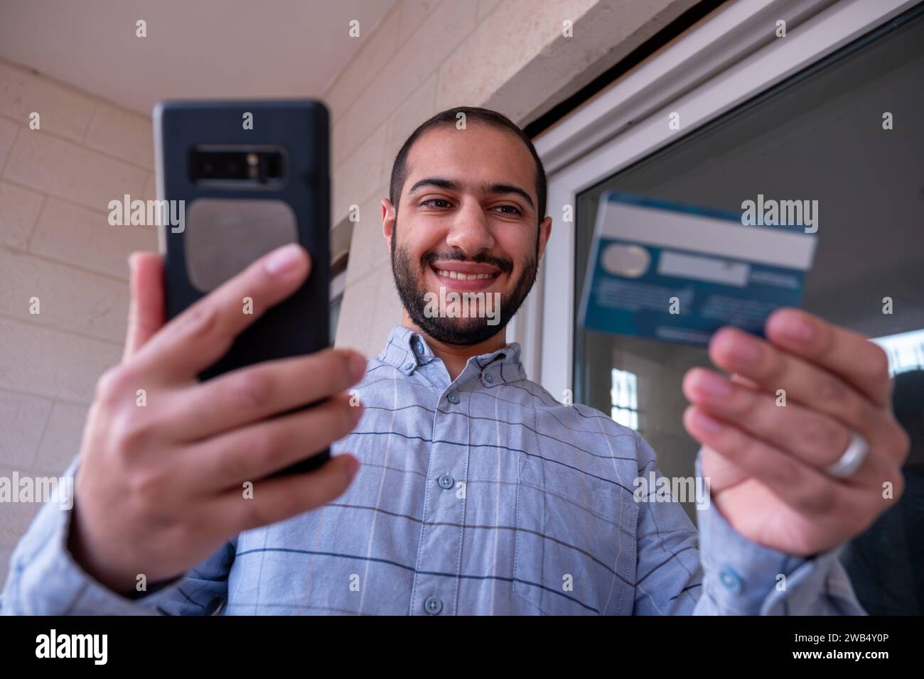 man using bank card with mobile phone to pay online for his order ...