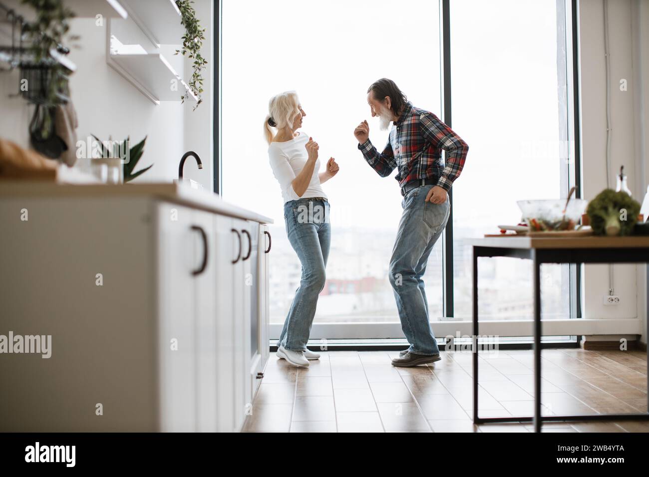 Old couple spends free time dancing twist in modern light kitchen Stock ...