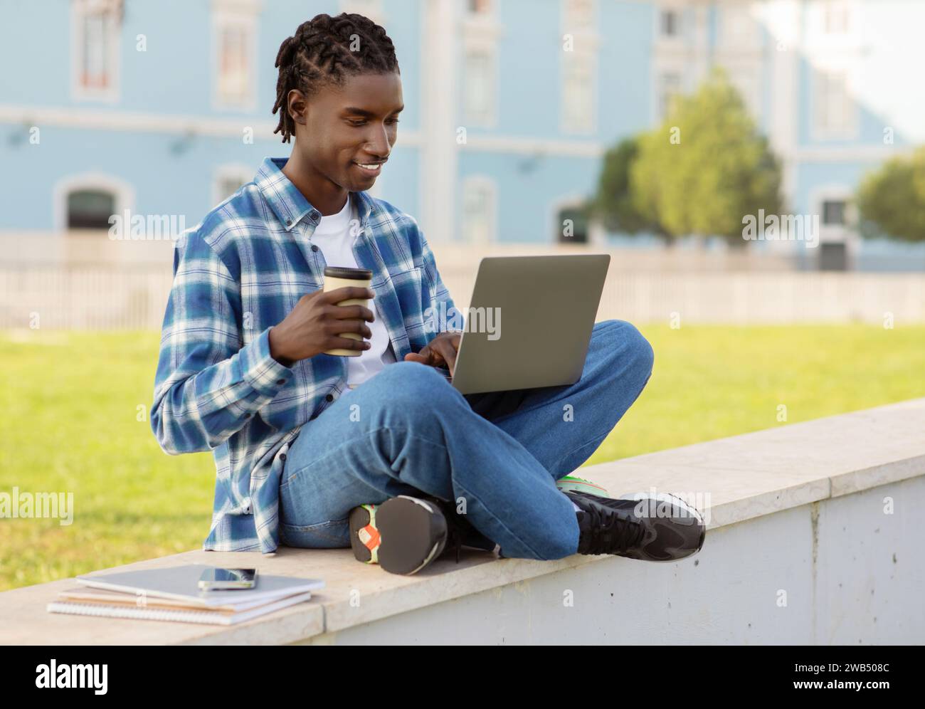 Happy black student guy studying online using laptop computer outdoors ...