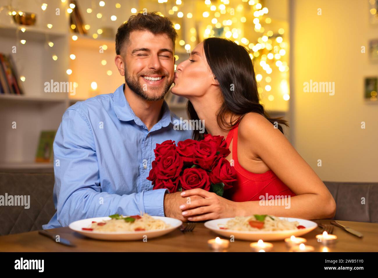 Happy couple at dinner, woman kissing man's cheek Stock Photo - Alamy