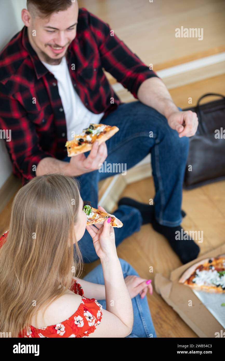A boy and girl eat pizza while sitting on the stairs at home Stock ...