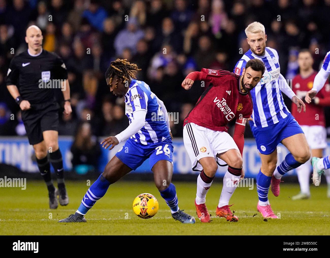 Wigan, UK. 8th Jan, 2024. Baba Adeeko of Wigan Athletic tackles Bruno ...