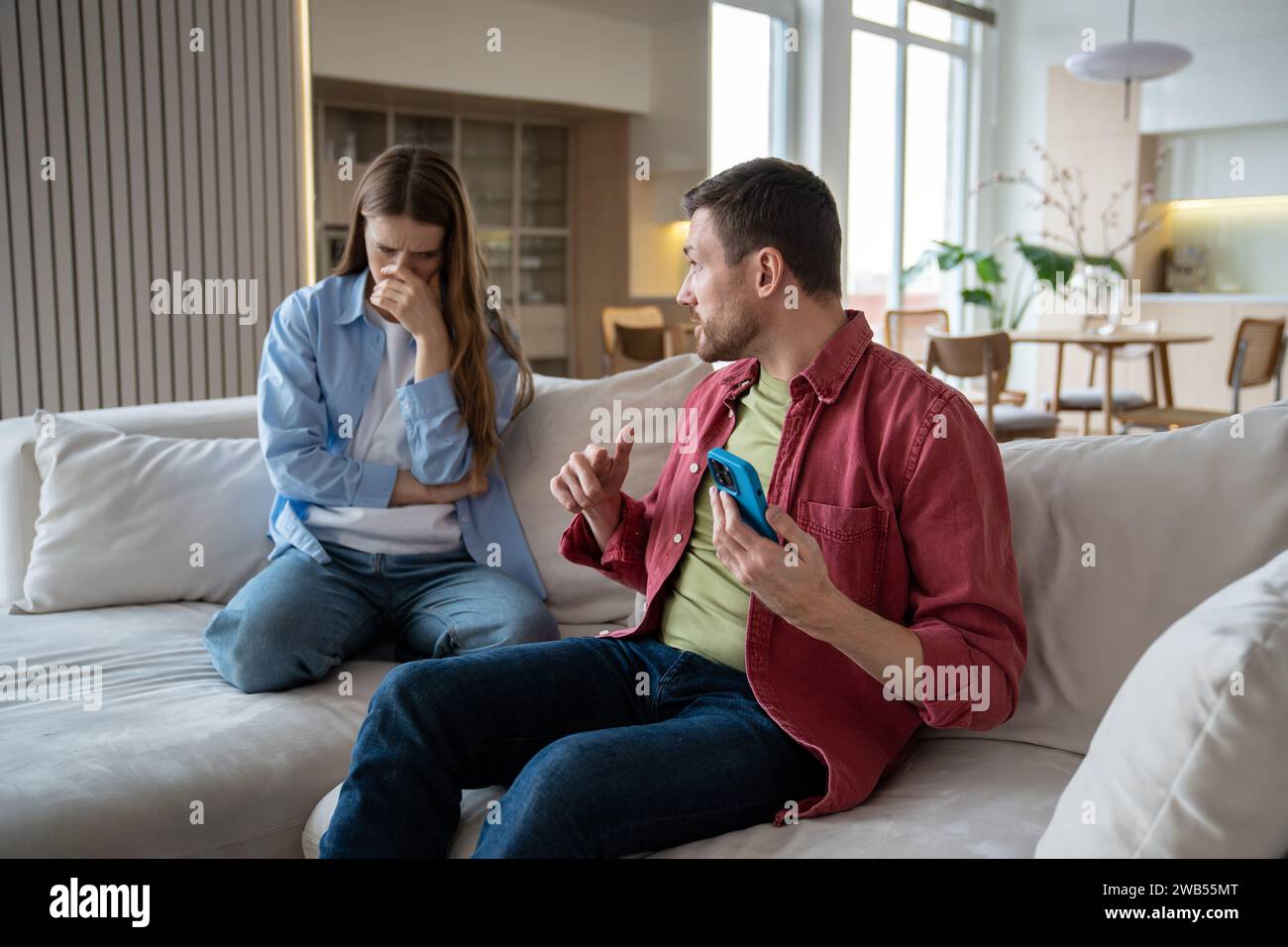 Annoyed wife listening explanations of cheater husband hiding phone ...