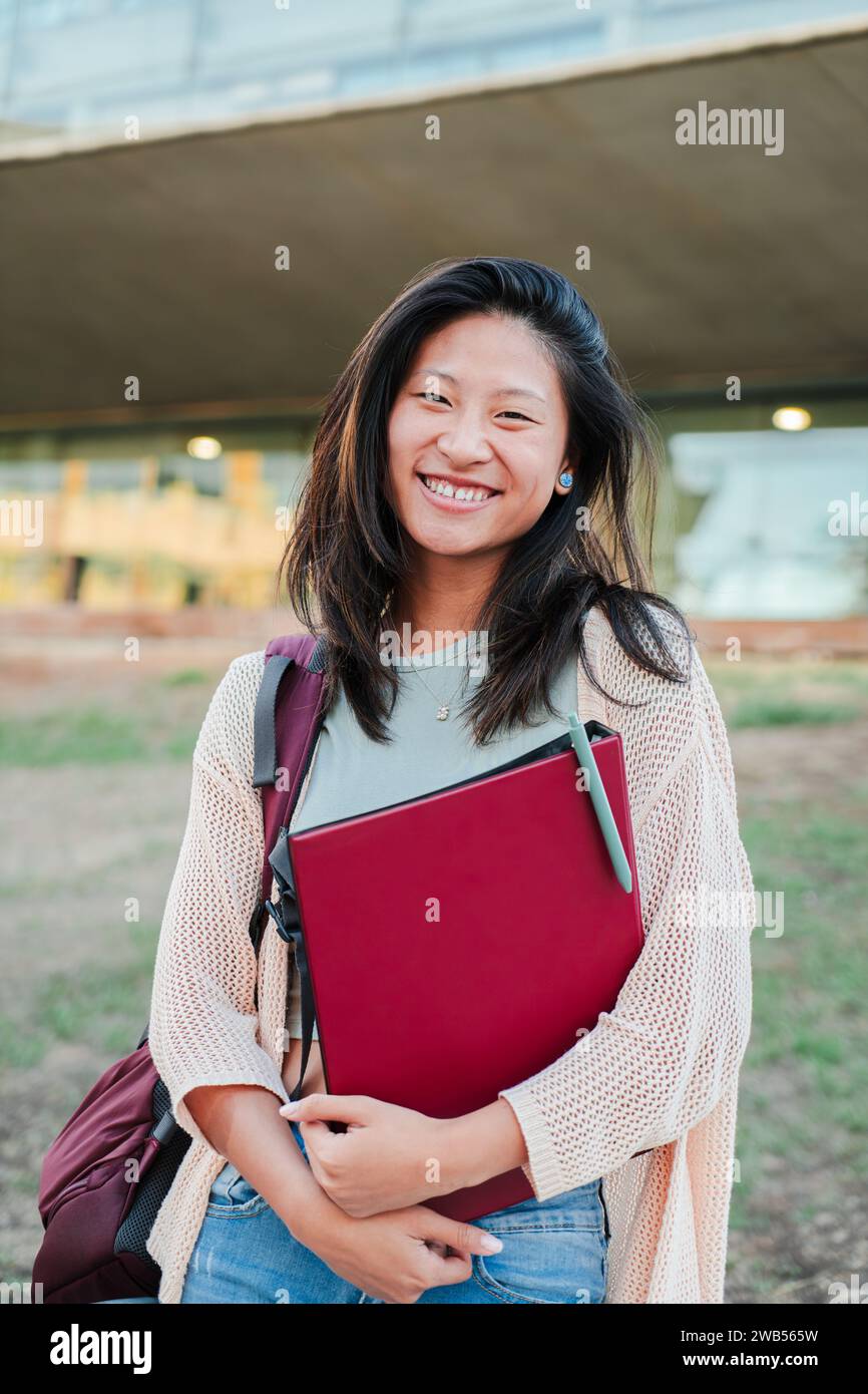 Vertical portrait of a chinese school girl smiling and looking at ...