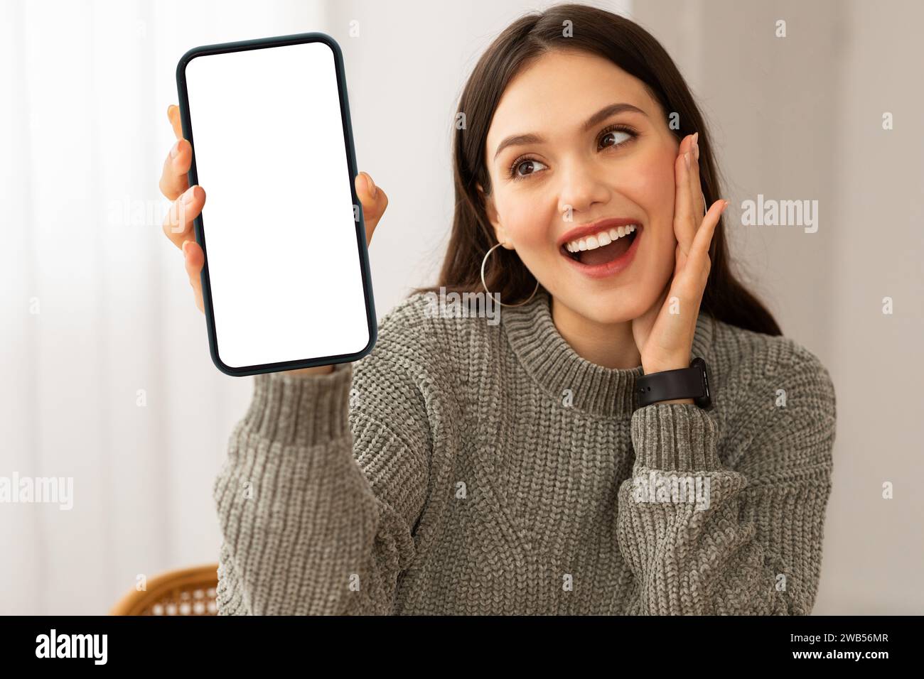 Amazed young lady looking smartphone with white screen Stock Photo - Alamy
