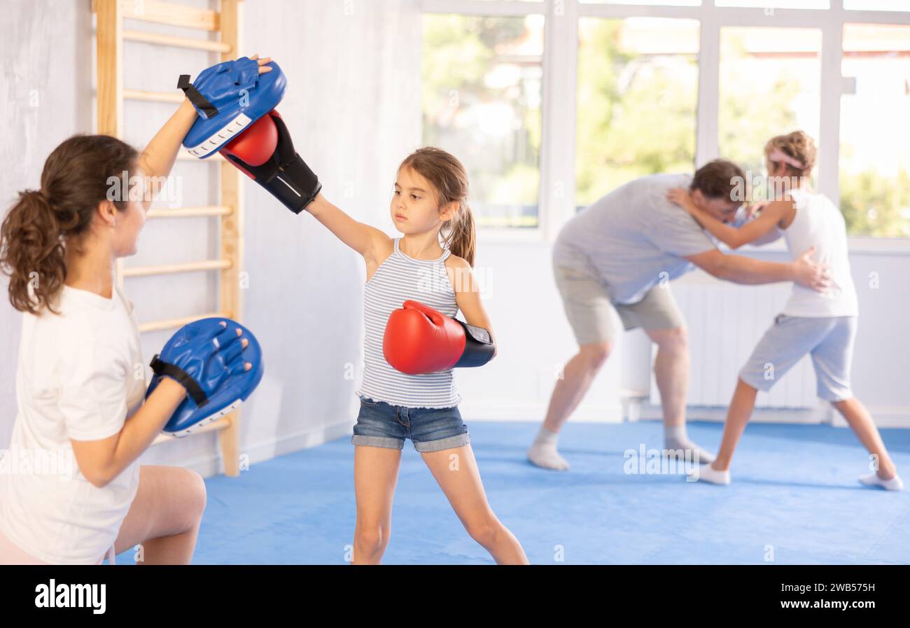 Little girl in boxing gloves learns to box from the punch mitts of her ...