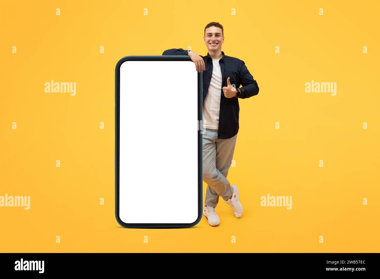 Positive stylish guy posing with big smartphone with empty screen Stock ...