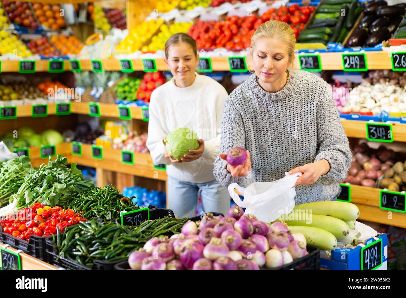 Friendly teenage girl and her mother shopping in fruit store Stock ...