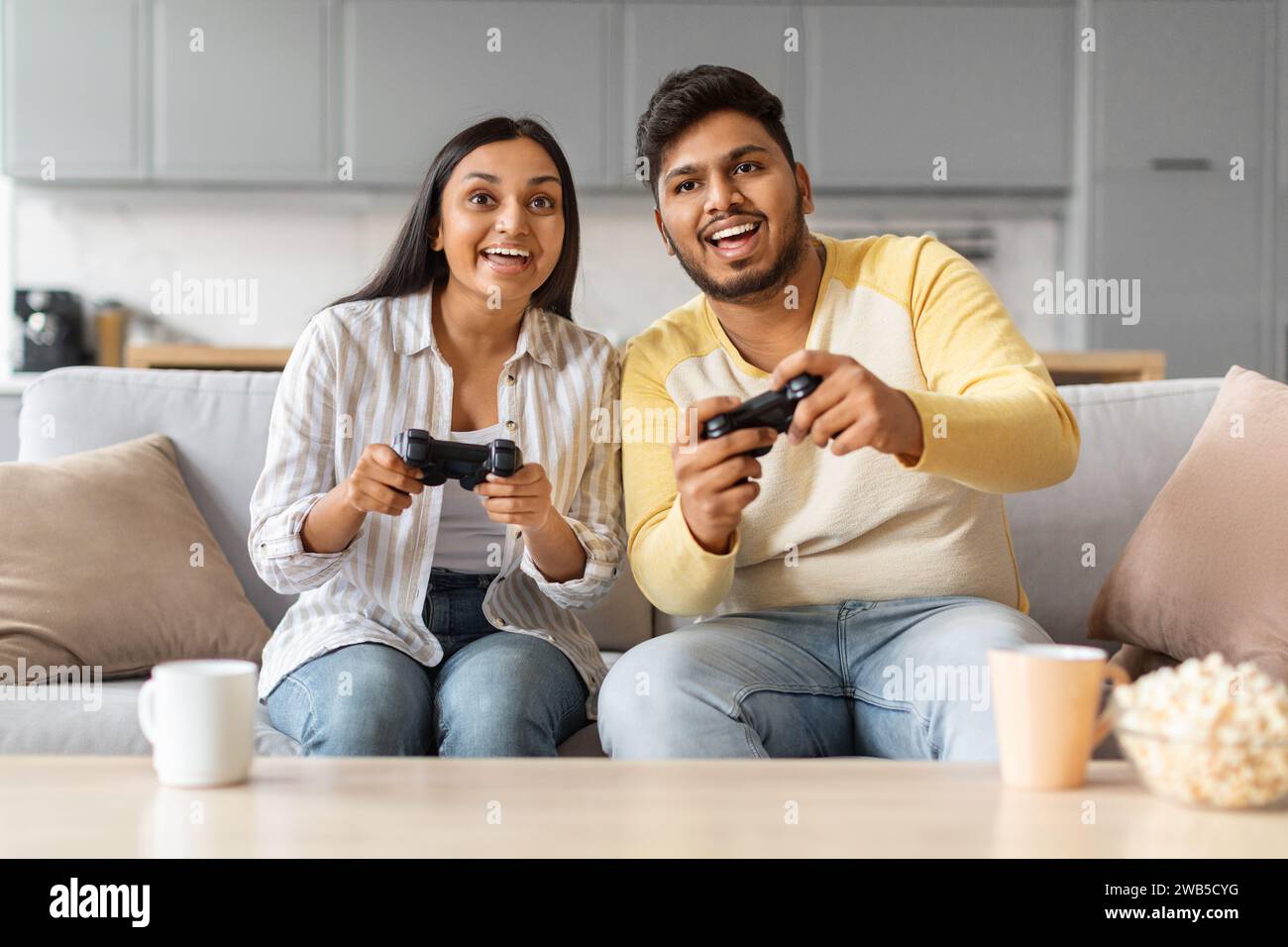 Young Indian Couple Playing Video Games With Joysticks At Home Stock ...