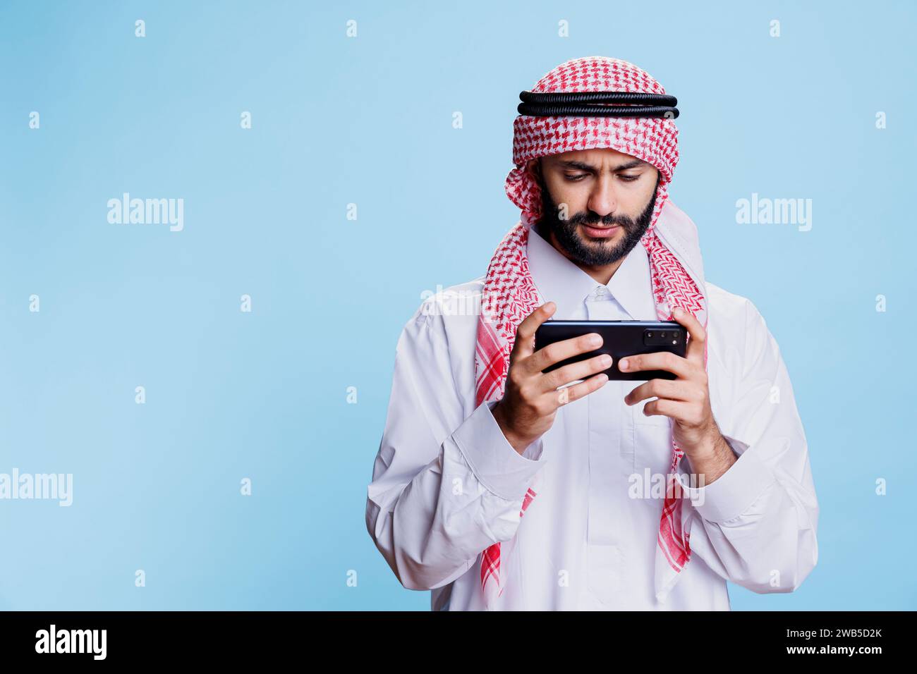 Arab man dressed in traditional attire enjoying leisure activity while ...