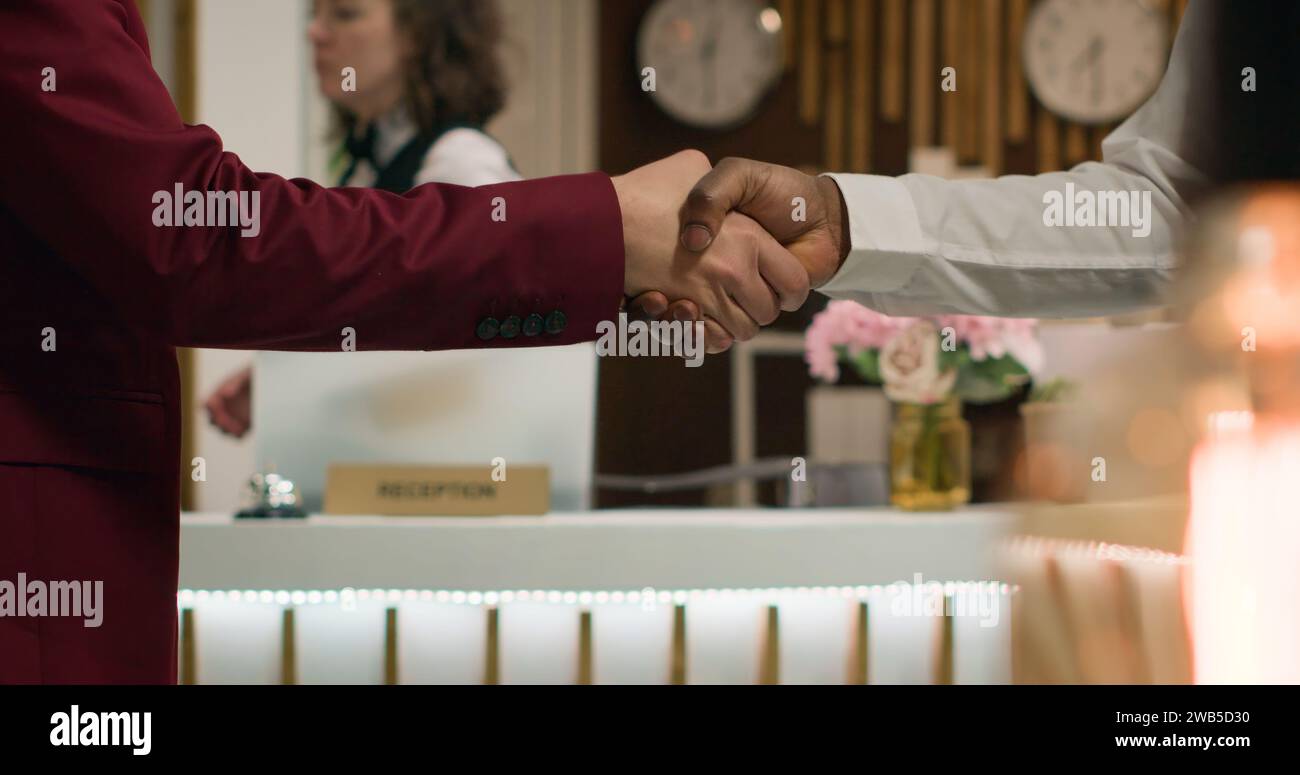 Bellboy shaking hands with hotel guest, greeting important businessman ...