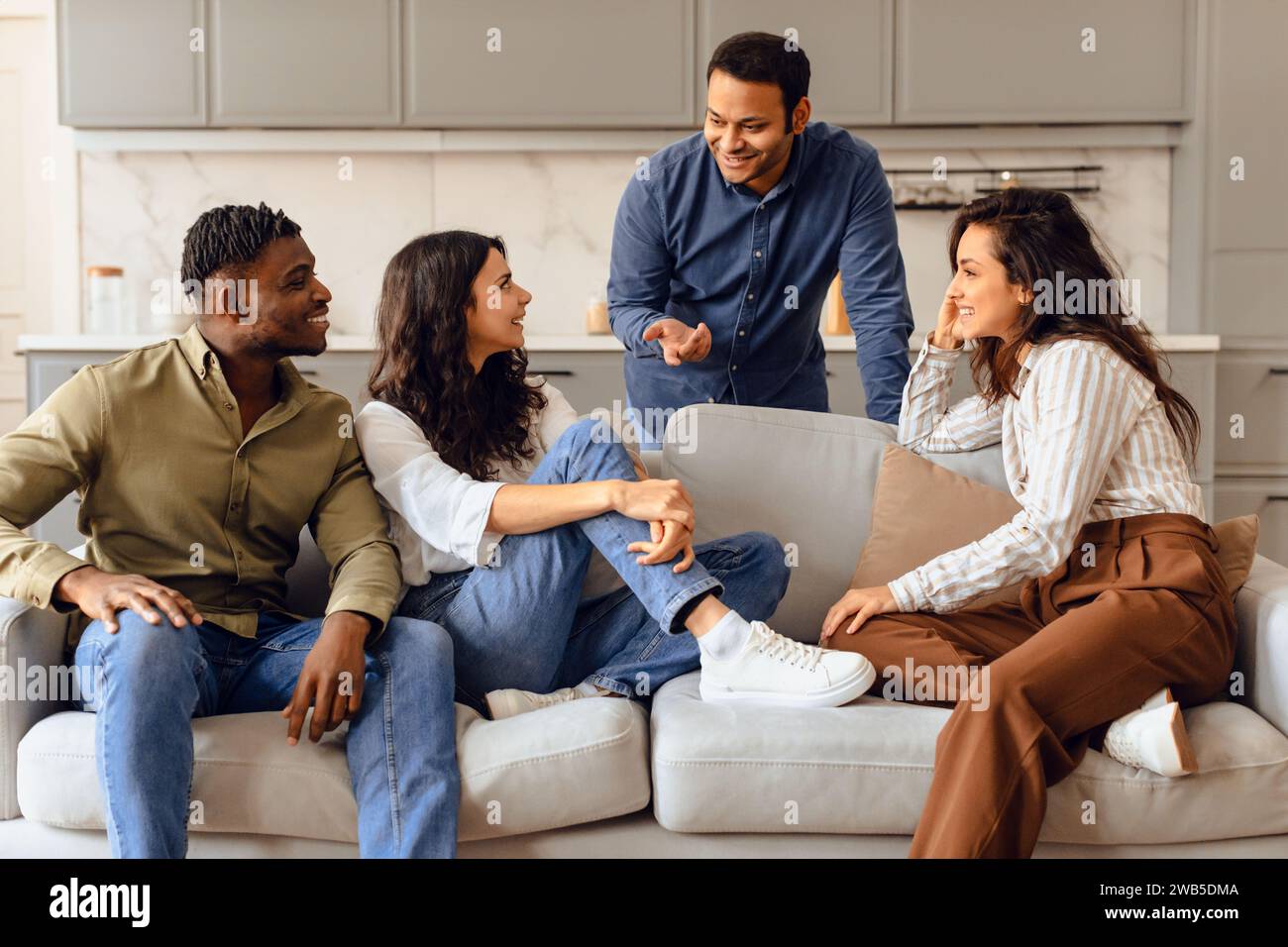 group of four diverse students talking sitting in living room Stock ...