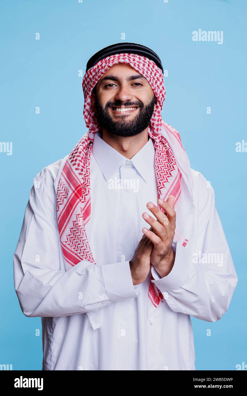 Excited muslim man in thobe and ghutra standing confidently, applauding ...